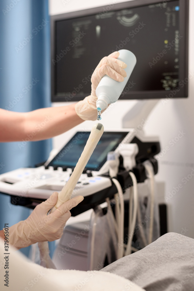 Gynecologist applies gel to a transvaginal ultrasound scanner for a ...