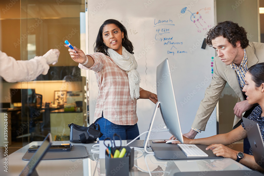 Co-Workers talking at computer in office while woman is working on dry ...
