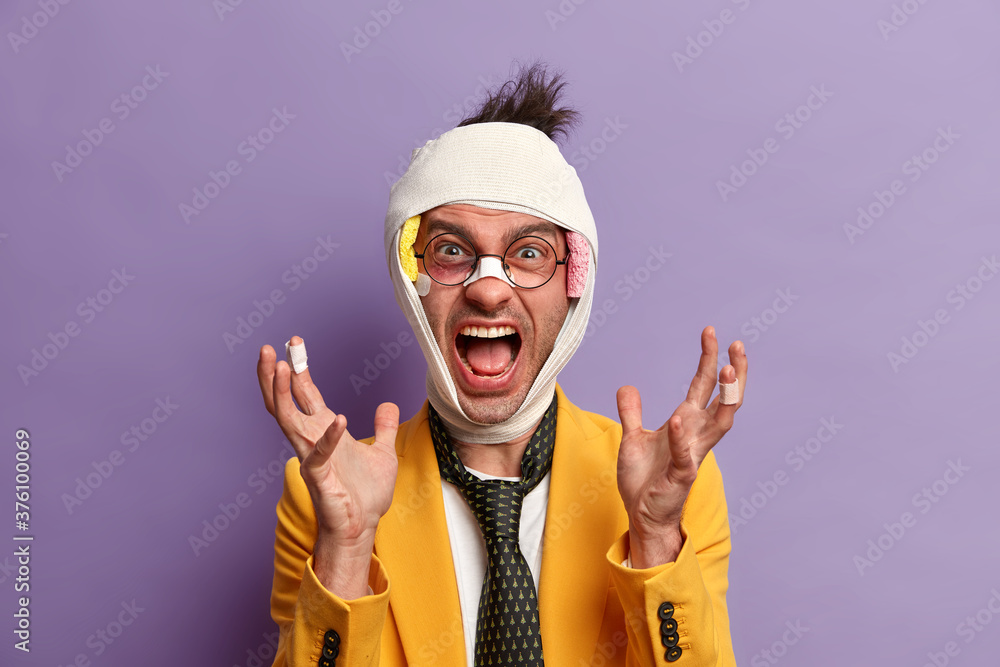 Irritated emotional man poses with angry expression, raises hands and ...