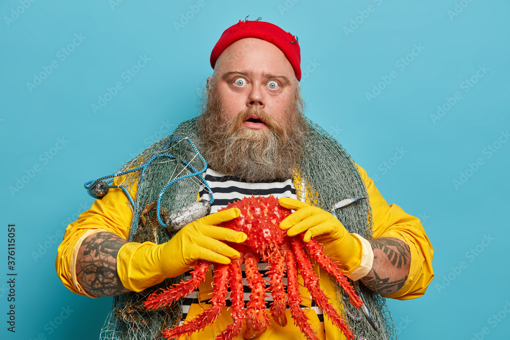 Shocked embarrassed bearded mariner with surprised expression holds big ...