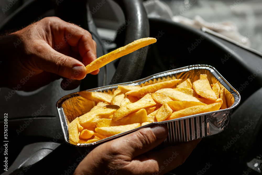 Man in the car eat yummy french fries in aluminium foil tray. Fast food ...