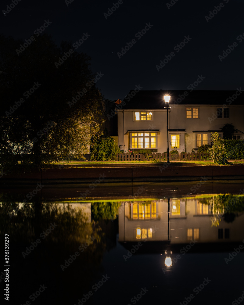 Reflections of an old english cottage lit by a street lamp reflecting ...