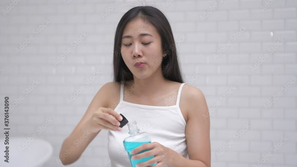 Daily routine concept. Young Asian woman gargling in the bathroom. 4k ...