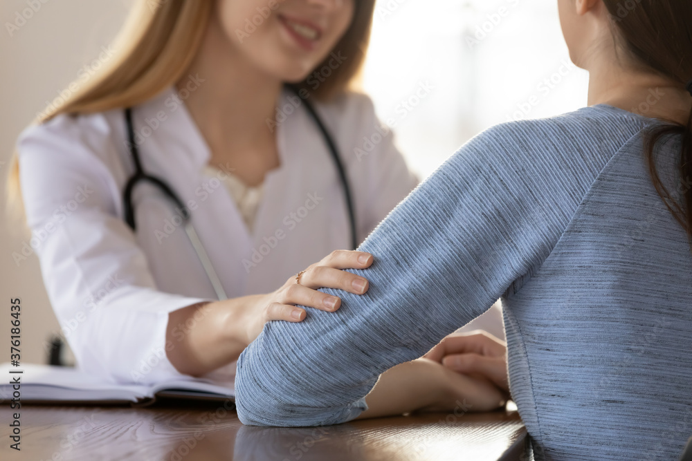 Caring female doctor wearing uniform comforting young woman patient at ...