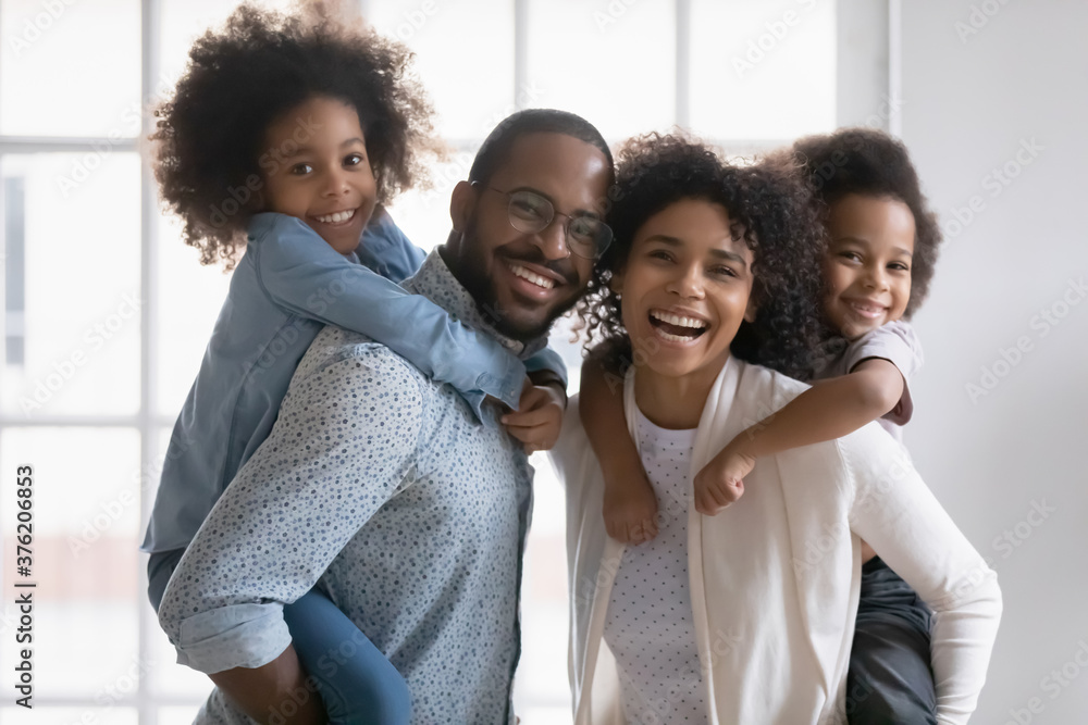 Portrait of happy biracial young couple parents giving piggyback ride ...