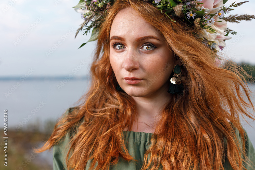 Slavic beauty with a flower wreath on her head in the lap of nature ...