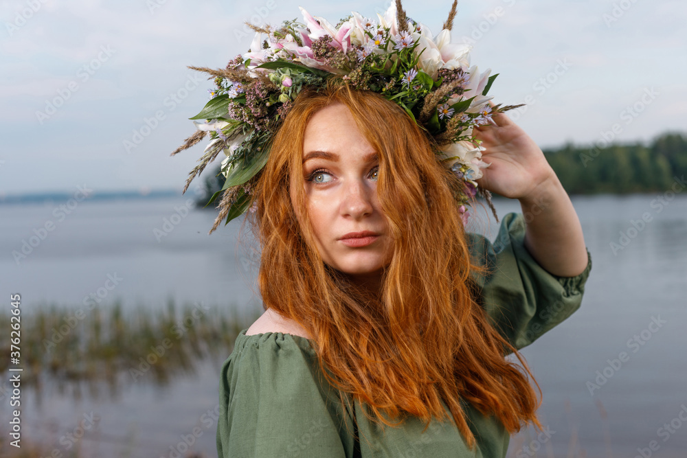 Slavic beauty with a flower wreath on her head in the lap of nature ...