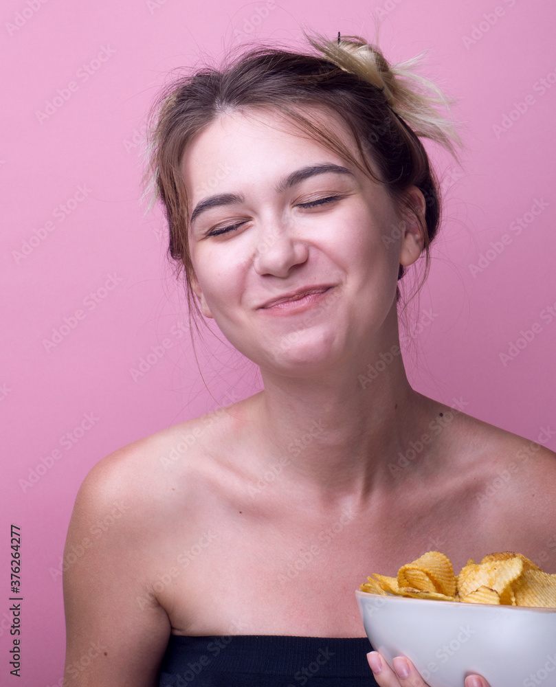 Hungry funny Woman eating potato chips on color pink background ...