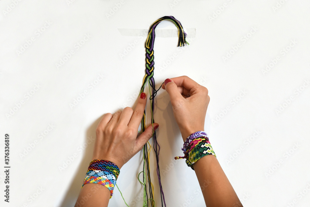 Female hands weaving knot for DIY friendship bracelet Pigtail. Many ...