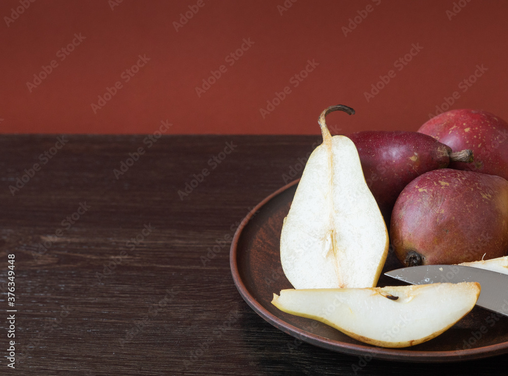 Ripe organic red and yellow pears and slices of pears in a clay bowl ...