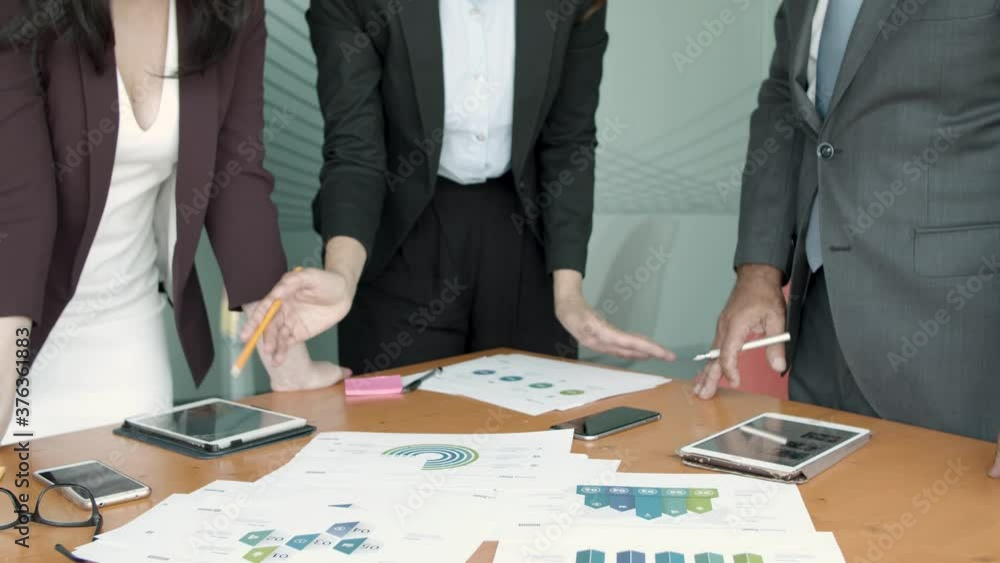 Business group standing at table with paper reports and documents with ...