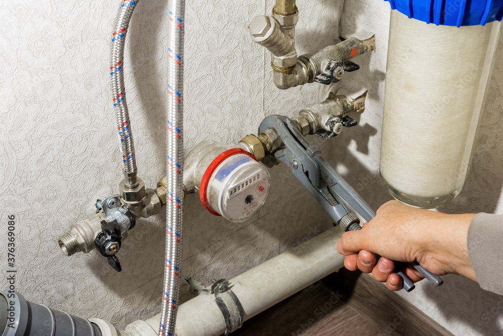 Repairing flat. Replacing the old water meter with a new one. Stock ...