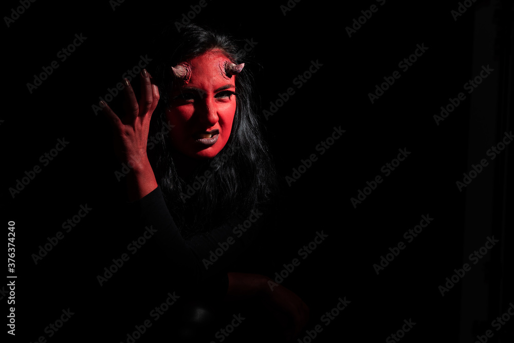 Halloween concept. Headshot of angry woman with red face makeup, wears ...