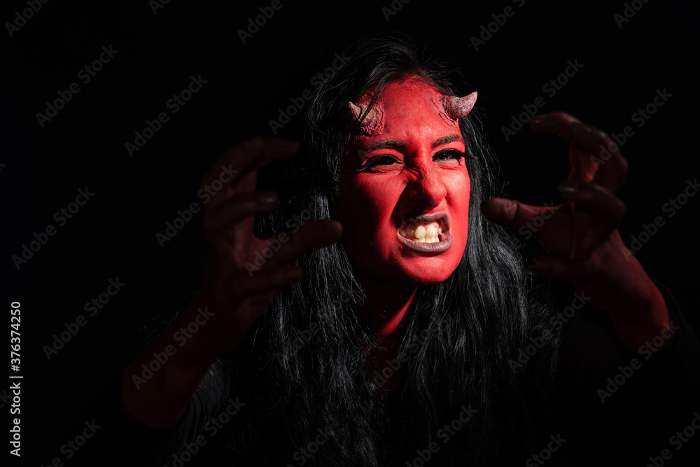 Halloween concept. Headshot of angry woman with red face makeup, wears ...