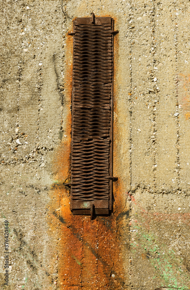 Rusty old ventilation grille on a concrete wall with streaks of rust ...