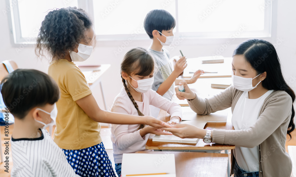 Female Asian teacher with medical face mask and using an alcohol spray ...