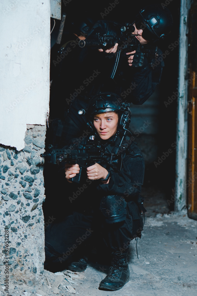 Special forces soldiers in black uniform aiming with a rifle from the ...