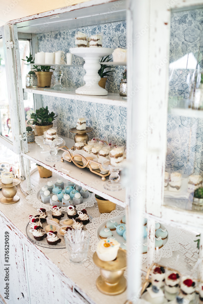 Side view of white old fashioned cupboard filled with candies, cupcakes ...