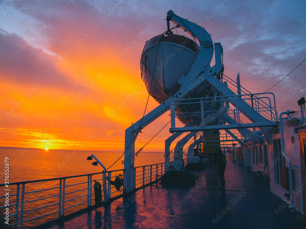 Lifeboat on a cruise ship or ferry at a romantic evening sunset setting ...