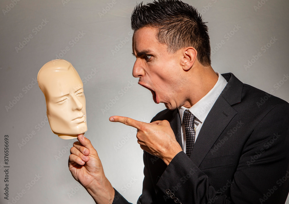 Man in business suit pointing and yelling at a caucasion plastic mask ...