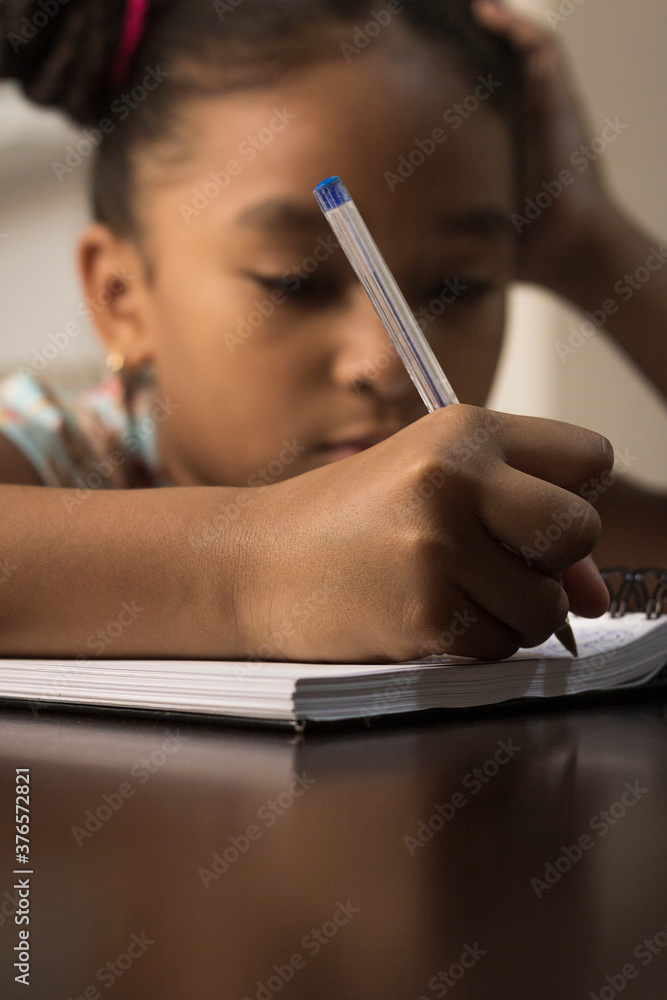 Niña escribiendo la tarea en un cuaderno Stock Photo | Adobe Stock