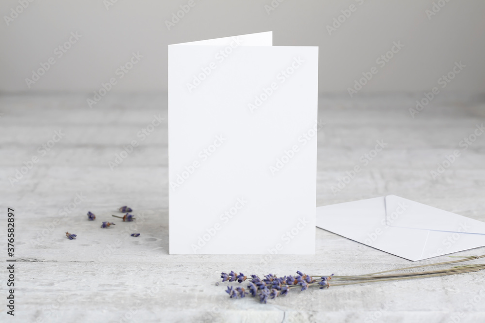 One white greeting card mockup, standing upright on a white wooden desk ...