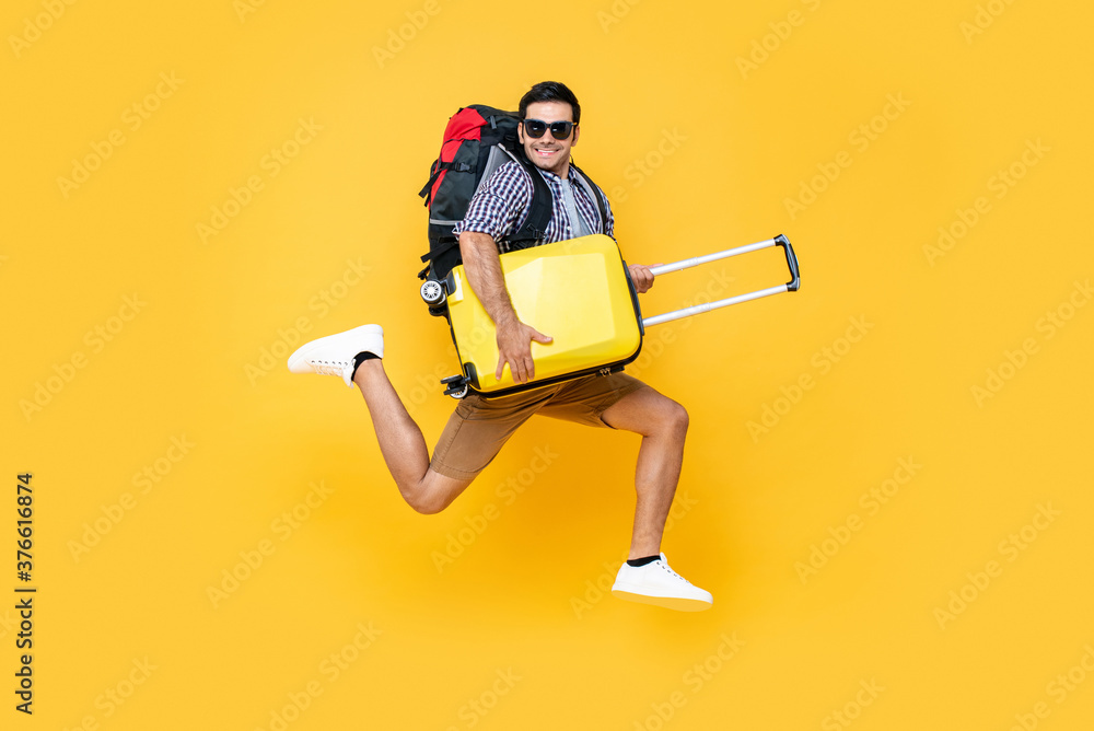 Young excited Caucasian male tourist with baggage jumping in mid-air ...