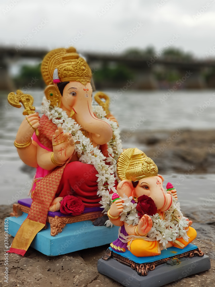 Side view of two ganpati idols on the rock near the river side. Ganpati ...