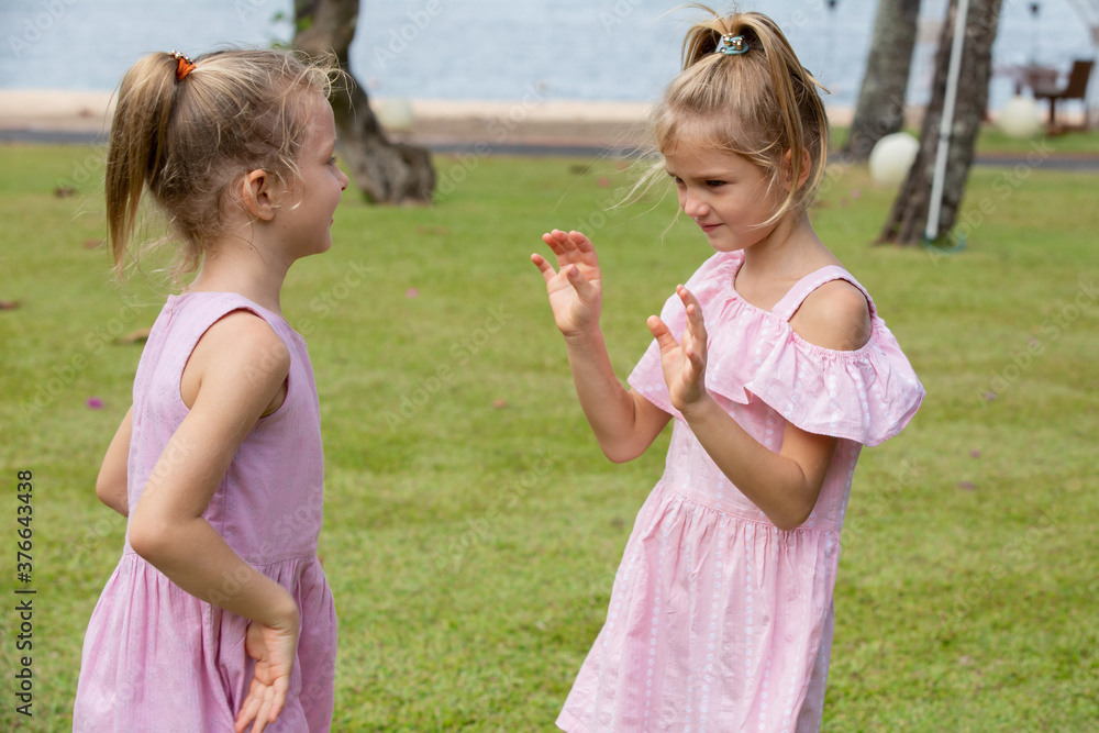 Two girls playing hand clapping game outdoors by the sea. Sisters ...