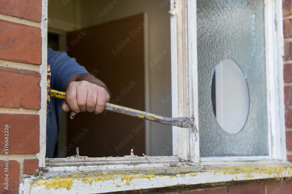 Crowbar being used to remove an old wooden window frame in brick wall ...