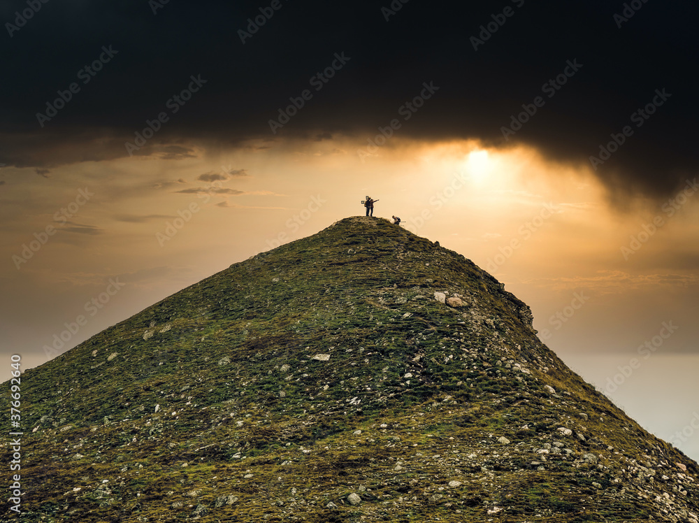 Dramatic landscape with three hikers reaching the top of the mountain ...