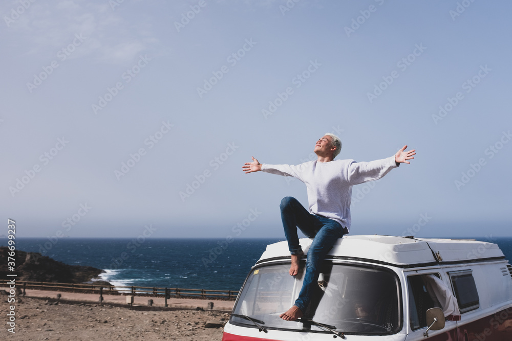 one man alone and isolated standing with opened arms on a minivan or ...