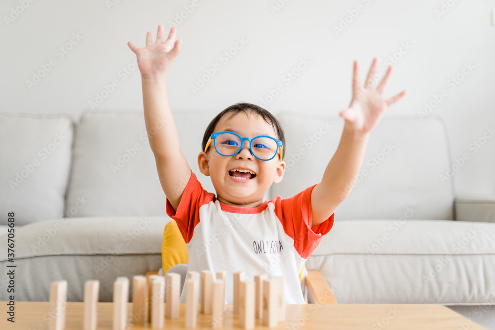 Happy smart and nerd toddler asian boy raised hand when he win play ...
