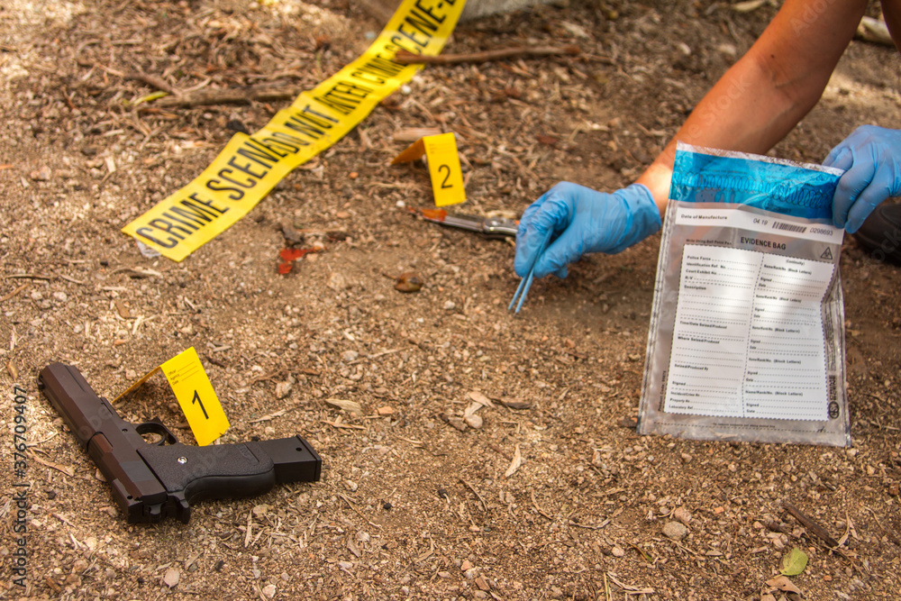 close up of a detective hand removing evidence of the crime like gun or ...