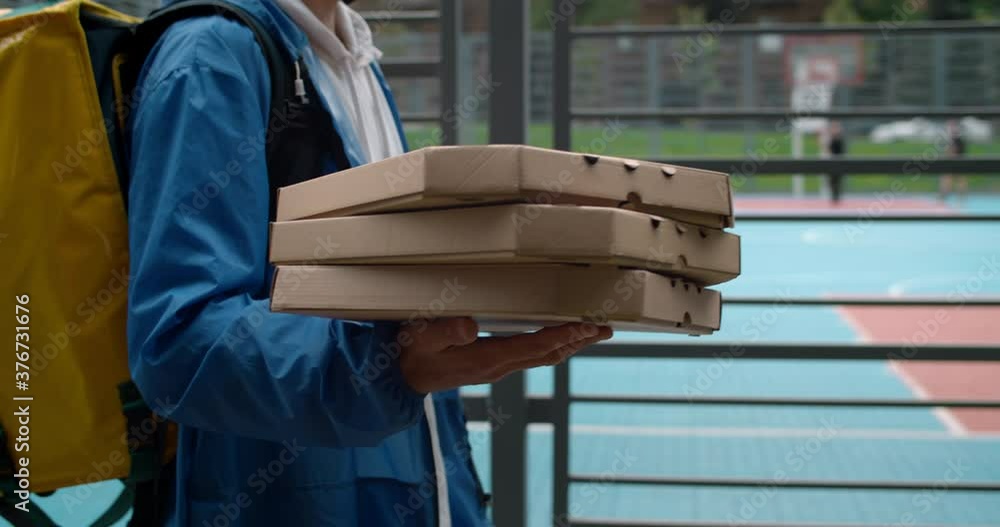 Courier carrying pizza boxes while delivering order to customer. Back ...