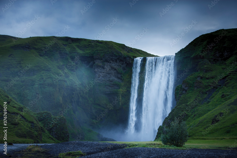 Skogafoss waterfall and grass covered mountains, Rangarvallasysla ... Skogafoss waterfall and grass covered mountains, Rangarvallasysla ...
