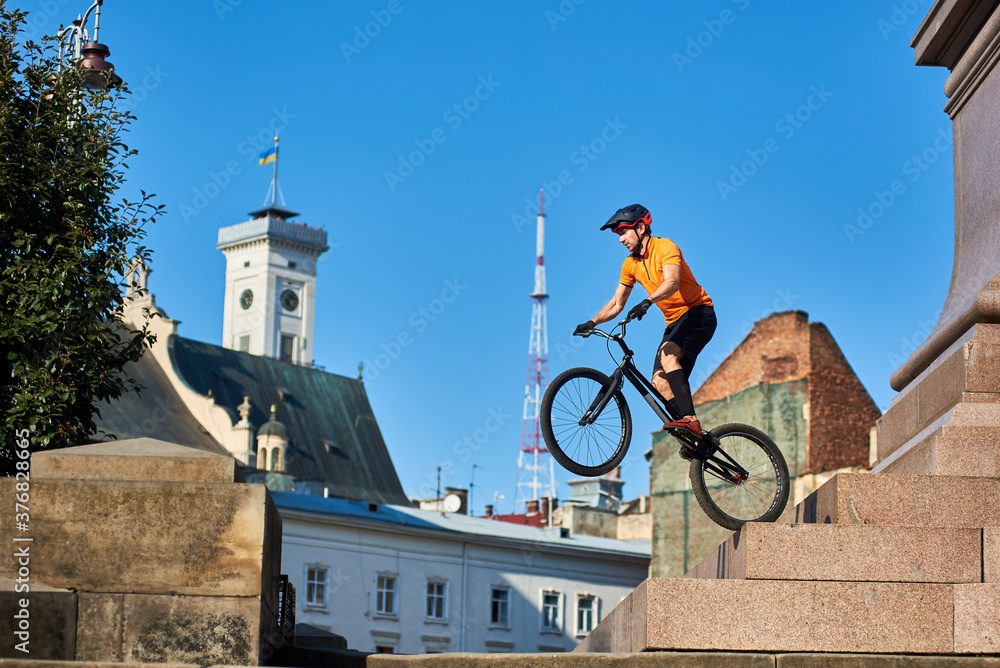Horizontal side snapshot of a freestyle trial biker performing extreme ...