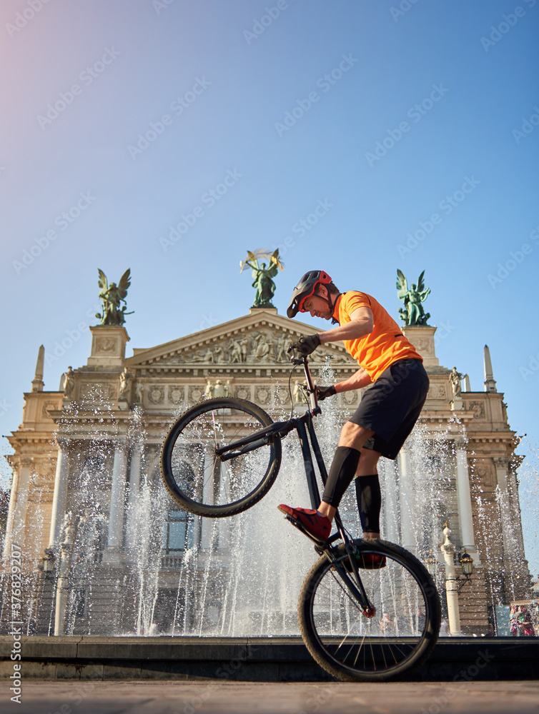 Extreme sportsman performing dangerous ride on mountain bike back wheel ...