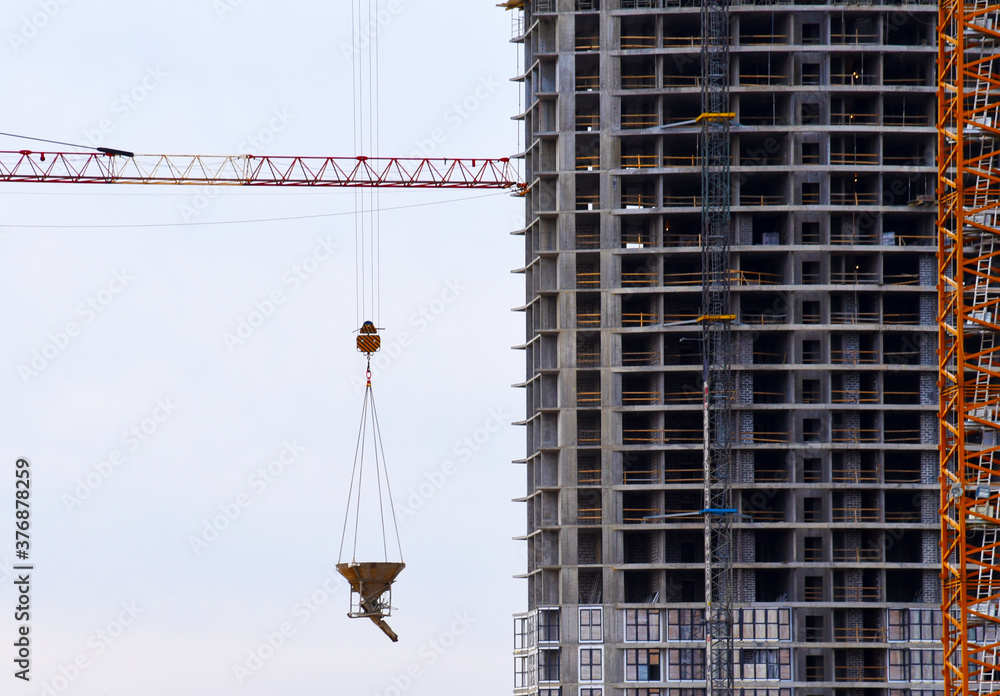 Tower crane lifting a concrete bucket for pour of concrete into ...