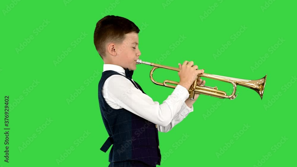 Young boy in a bow tie playing the trumpet swaying from side to side on ...