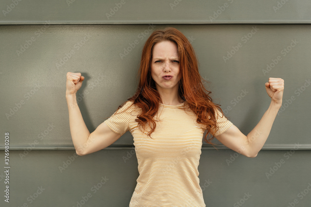 Macho young woman flexing her muscles Stock Photo | Adobe Stock