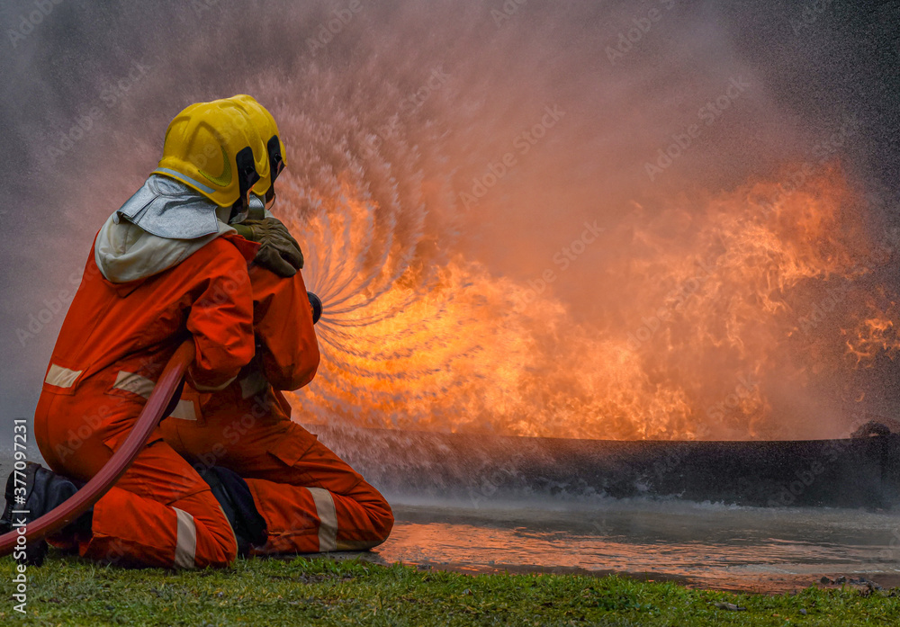 Two brave firefighter using extinguisher and water from hose for fire ...