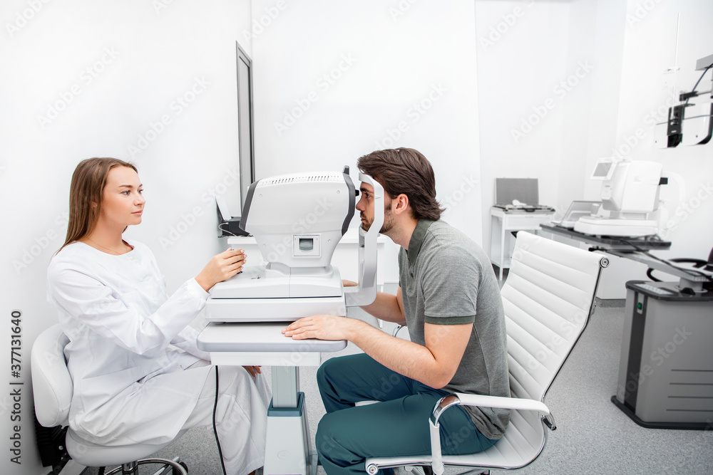 Experienced ophthalmologist woman using an autorefractor calculates the ...