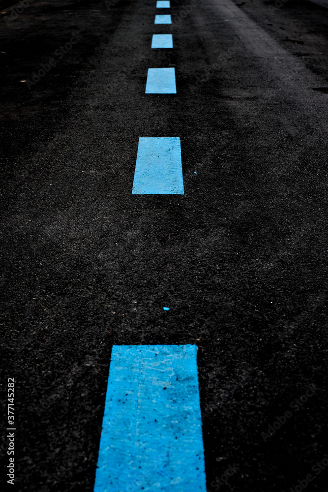 Dashed blue road marking line in perspective, centered in the frame ...