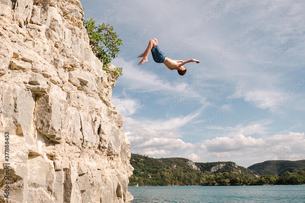 teen boy doing a backflip into a beautiful lake Stock Photo | Adobe Stock