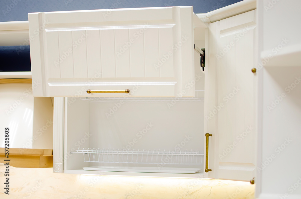 Lifting mechanism of the kitchen facade. A white kitchen cabinet opens ...
