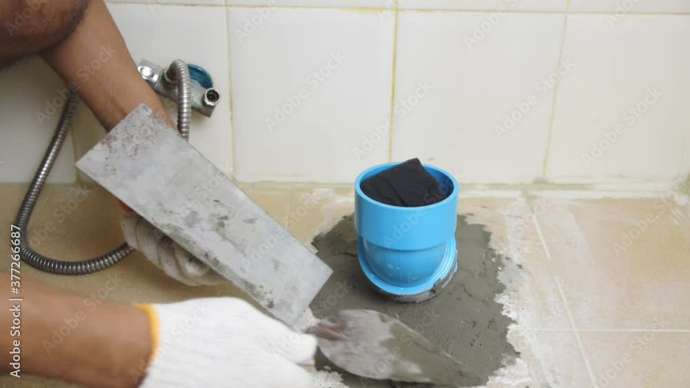 Construction workers are using plastering tools around the PVC pipe to ...