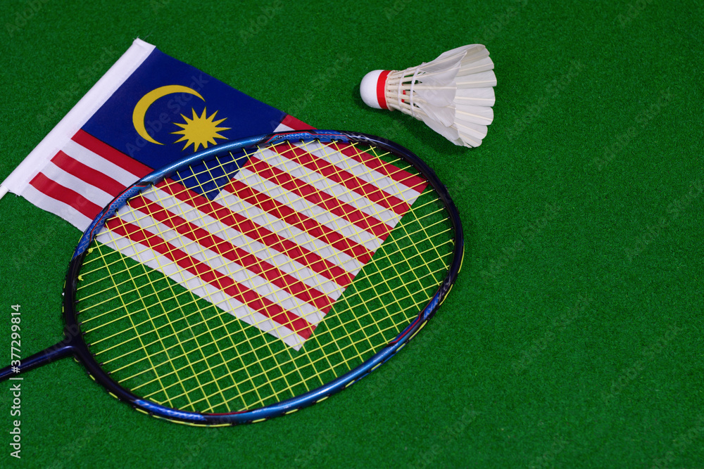 Racket and shuttlecock with Malaysia flag background on the green floor ...
