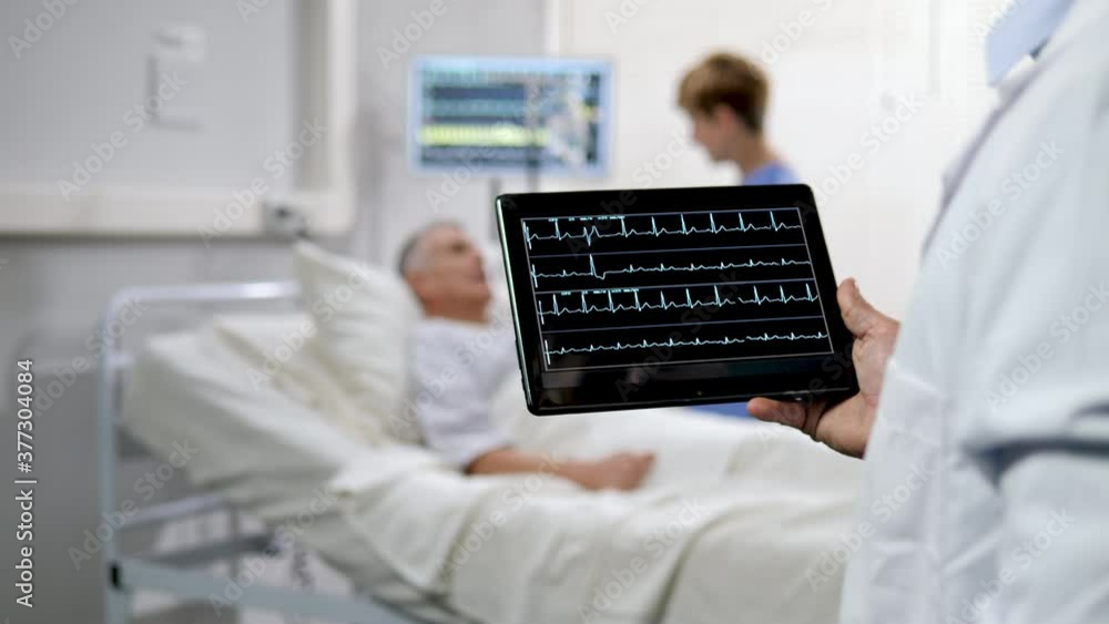 Close up on doctor hand holding tablet showing livestream ecg ...