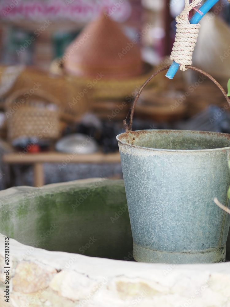 Zinc water bucket hang by hemp rope on Artesian well made of cement ...